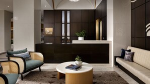 Um lobby moderno com balcão de recepção, área de estar e um arranjo floral decorativo.