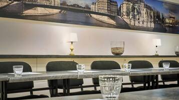 Uma sala de conferências com uma mesa comprida, quatro cadeiras e duas luminárias.