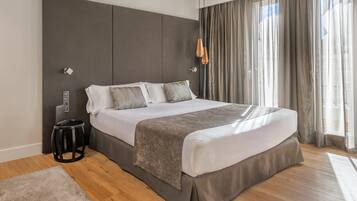 Quarto moderno com uma cama grande, mesa de cabeceira e janela com cortinas.