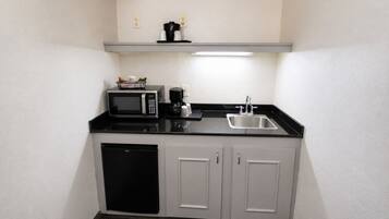 Uma cozinha compacta equipada com micro-ondas, cafeteira e pia.
