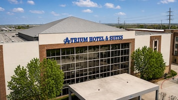 Um hotel moderno com fachada de vidro ampla e uma placa indicando 'Atrium Hotel & Suites'.