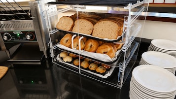 Vitrine de padaria com pães, bagels e muffins.