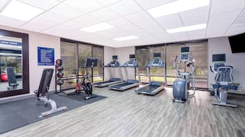 Ginásio com esteiras, equipamentos elípticos e aparelhos de musculação.