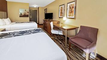 Quarto de hotel com duas camas, uma escrivaninha, uma cadeira, televisão e obras de arte nas paredes.