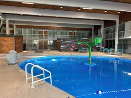Uma piscina interior com cesto de basquete, área de estar e vista para o interior do edifício.