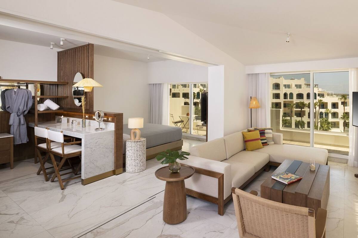 Quarto de hotel moderno com cama, sofá, televisão e varanda com vista.
