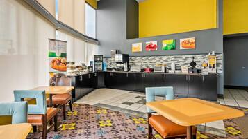 Restaurante com interior moderno, apresentando uma área de cozinha, assentos com mesas e cadeiras, e um tapete estampado.