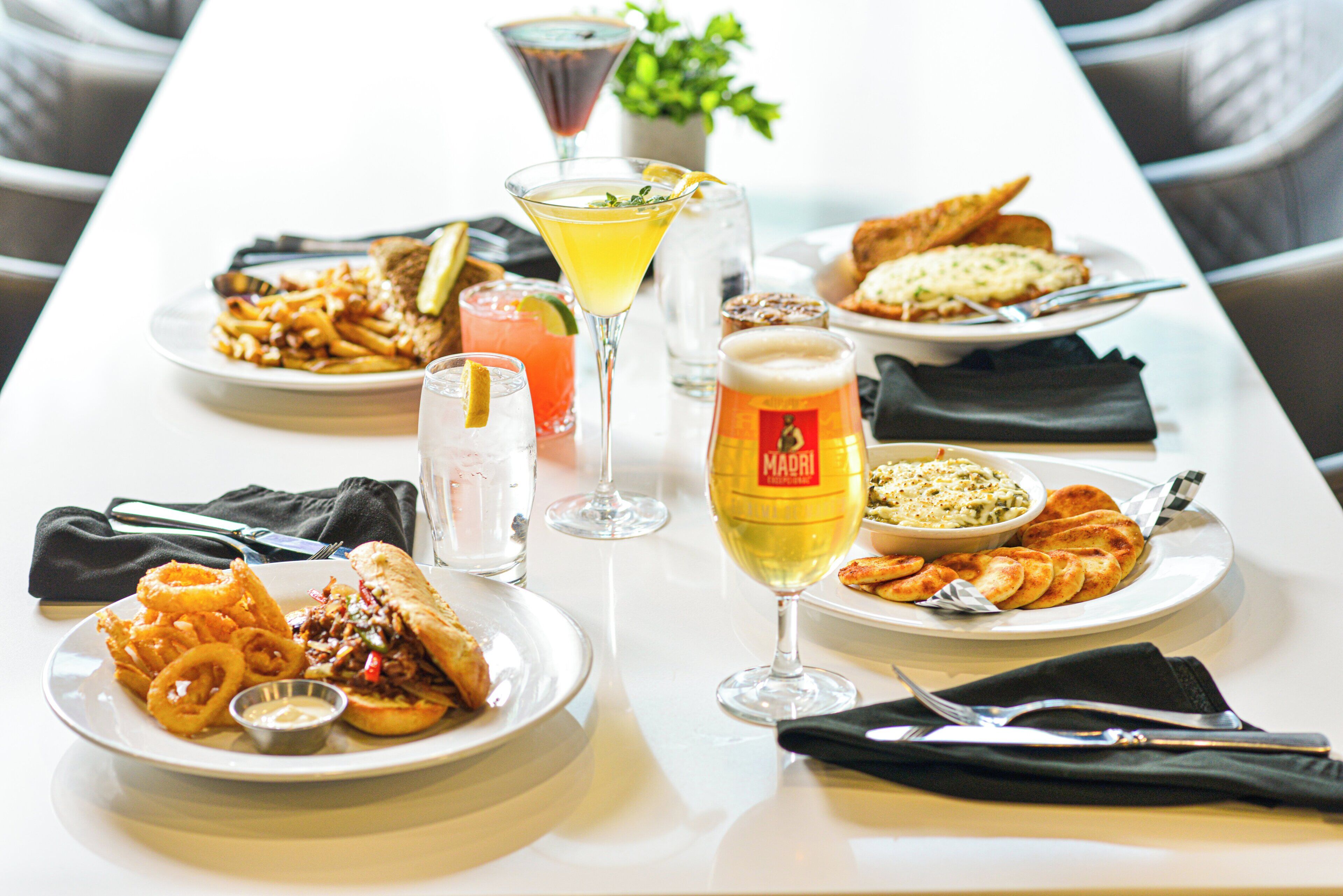 Uma mesa de jantar com diversos pratos, bebidas e utensílios.
