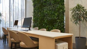 Um espaço de escritório moderno com uma mesa comprida, várias cadeiras, um computador de mesa e uma impressora.