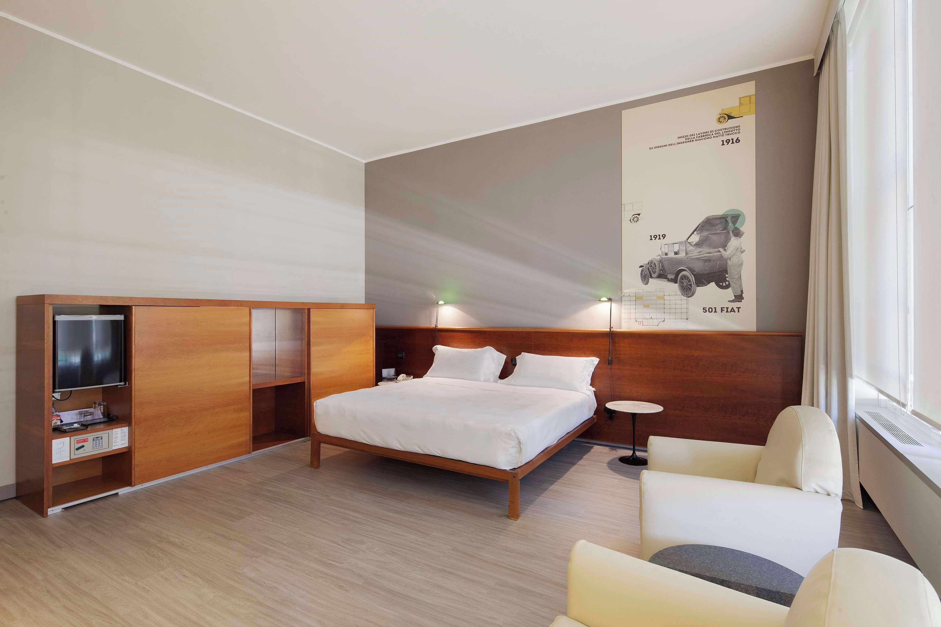 Quarto de hotel moderno com cama de madeira, televisão, guarda-roupa e um cartaz na parede.