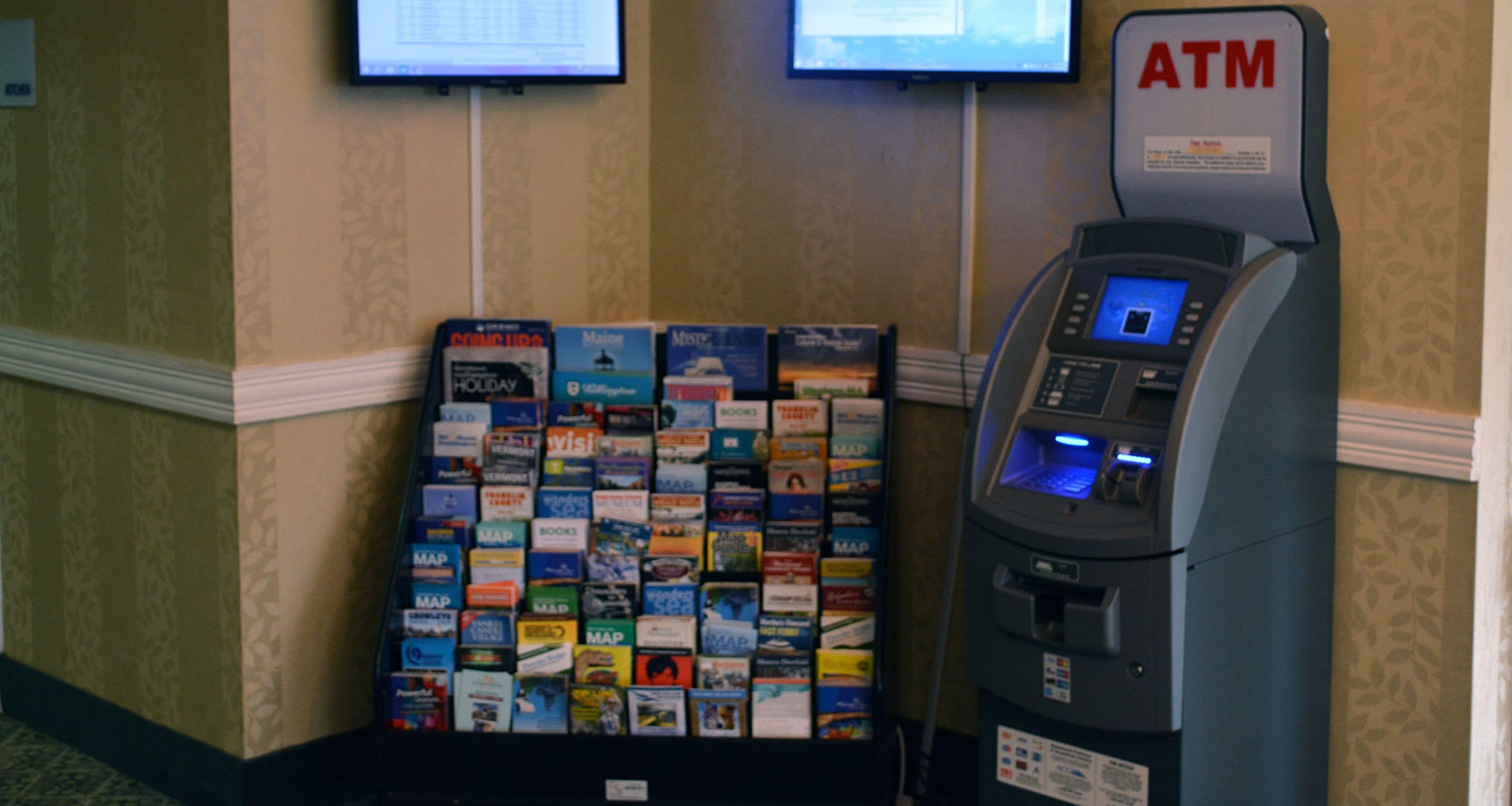Um caixa eletrônico e uma seleção de livros de viagem em um saguão de hotel.