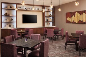 Quarto de hotel com televisão de tela plana, estantes de livros e áreas de estar.