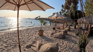 Uma praia com guarda-sóis, espreguiçadeiras e palmeiras.