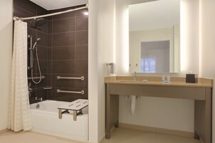 Uma casa de banho moderna com banheira, chuveiro e toucador.