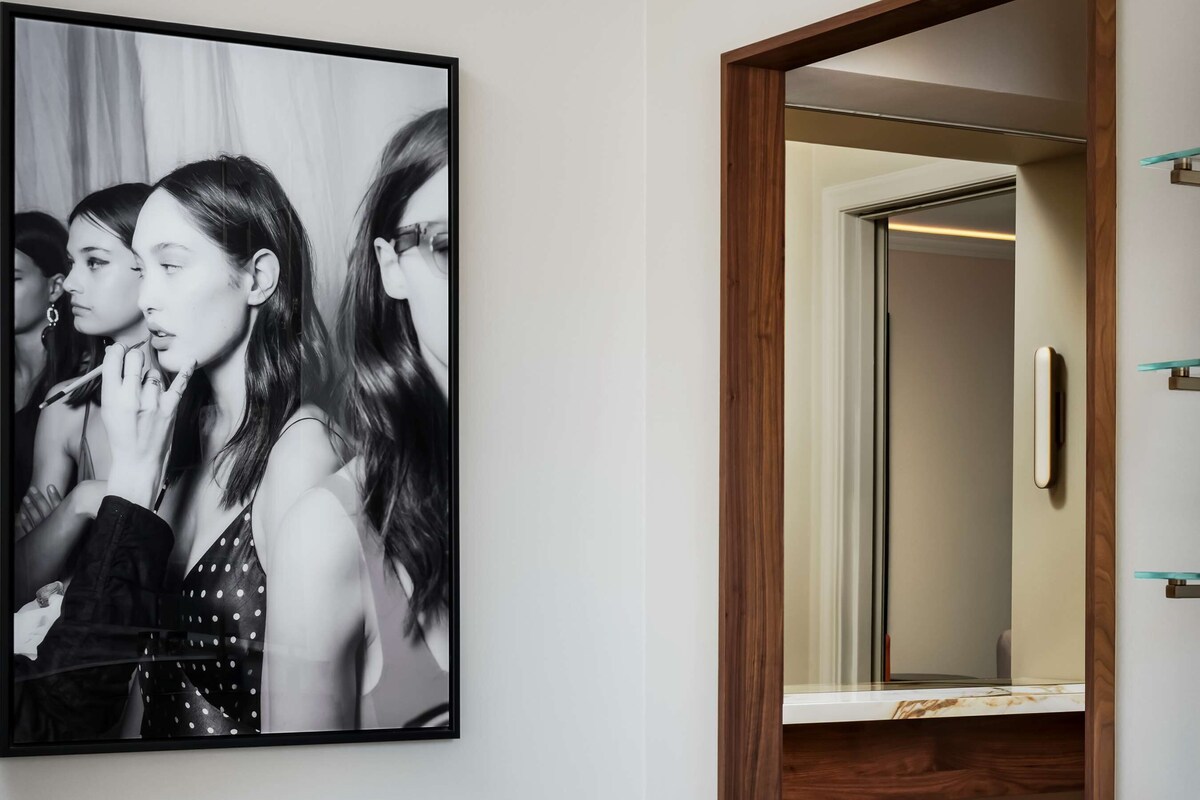 Quarto moderno com uma grande fotografia preto e branco emoldurada, um banco de madeira, um espelho e uma cômoda.