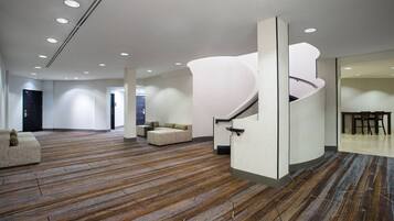 Um hall amplo com design moderno, apresentando uma estrutura arquitetônica única, área de estar e piso de madeira.