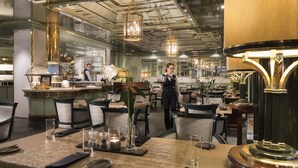 Um restaurante com área de bar, várias mesas e design de interiores moderno.