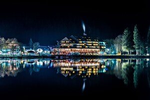 Um edifício de vários andares com varandas, refletido em águas calmas.