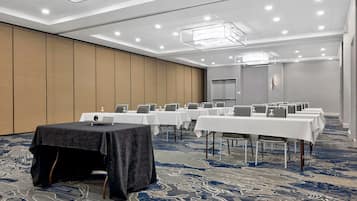 Uma sala de conferência com mesas, cadeiras e um projetor.