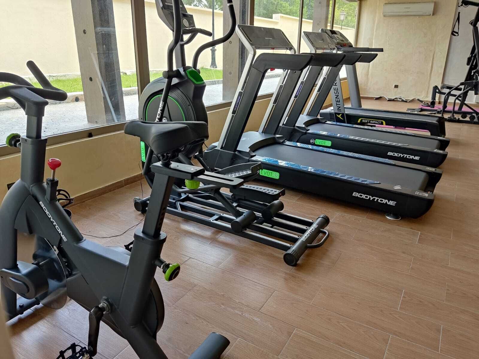 Uma academia com esteiras, elíptico e bicicleta ergométrica.