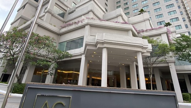 Um hotel com uma entrada imponente, uma bandeira e uma placa indicando ser um hotel Marriott.