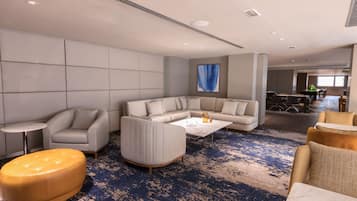 Uma sala de estar moderna com um sofá modular, um banquinho redondo e uma mesa de centro.