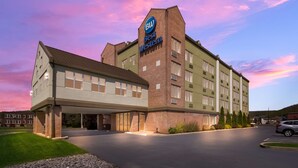 Um hotel com um grande letreiro 'BW Best Western', entrada coberta e estacionamento.