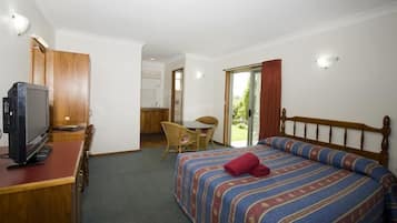 Quarto com cama, escrivaninha, televisão e vista para o exterior.