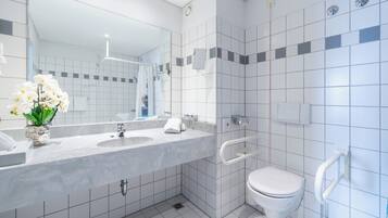 Uma casa de banho moderna com um espelho grande, duas bacias, uma sanita e uma área de duche.