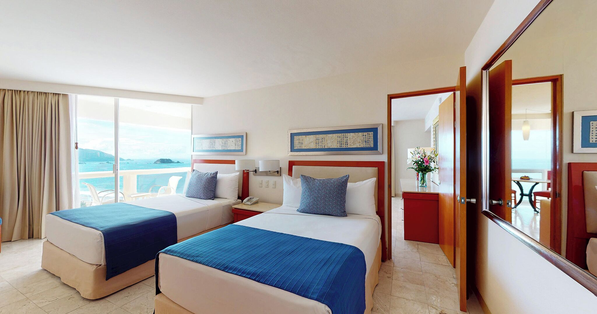 Quarto de hotel com duas camas, uma janela ampla com vista, uma escrivaninha e um espelho.