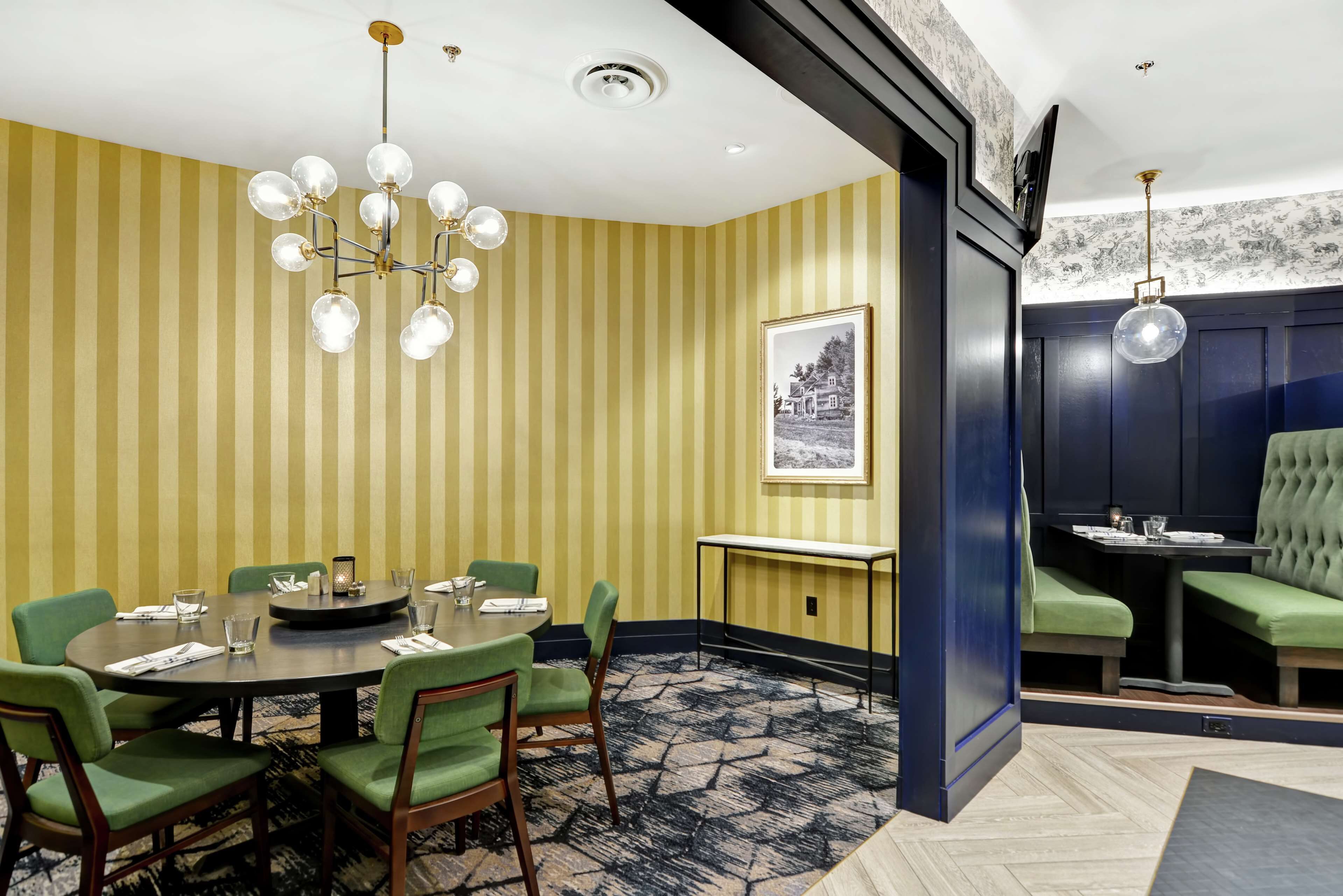 Uma sala de jantar com uma mesa redonda, cadeiras e um candelabro.