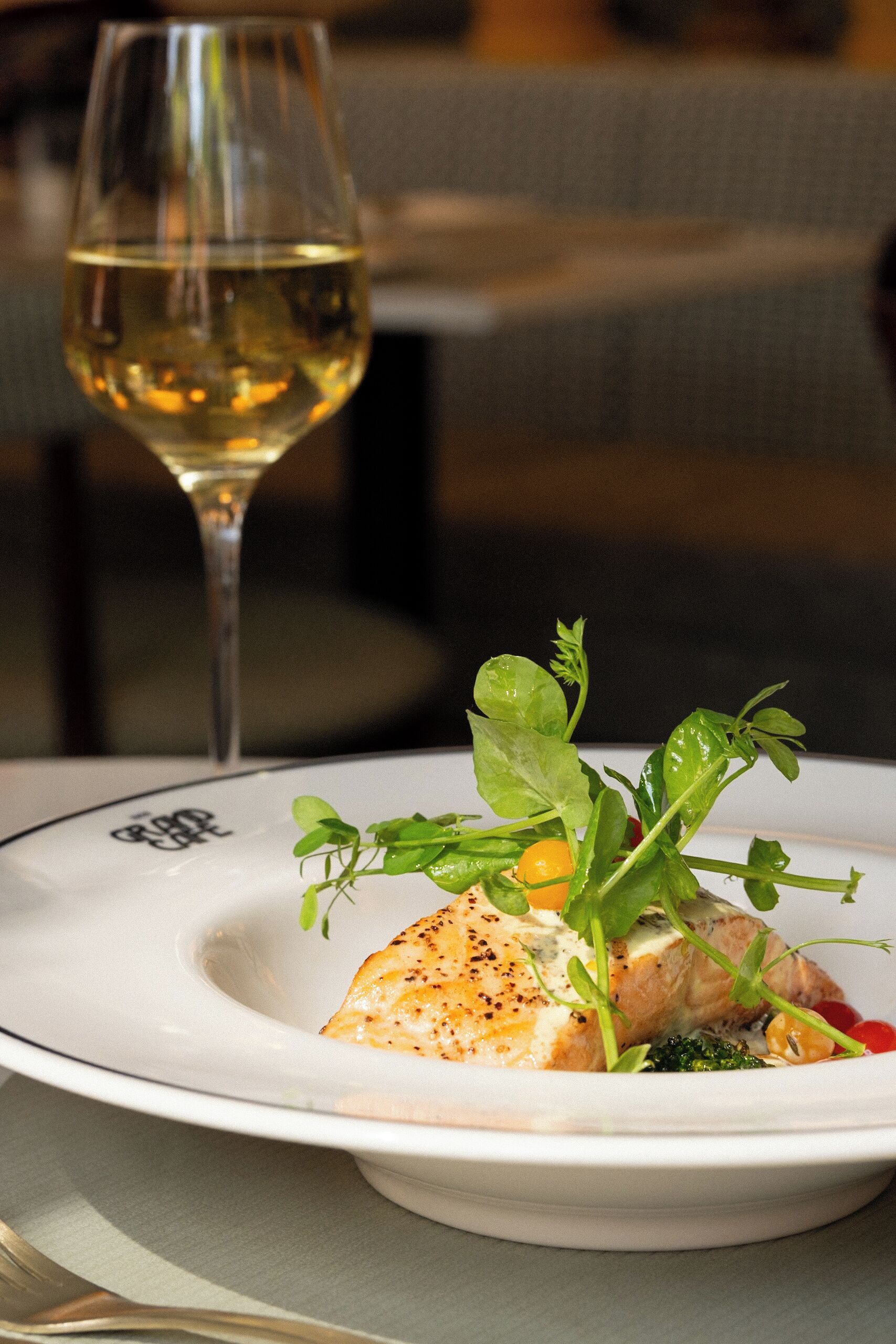 Prato de comida com um copo de vinho branco.