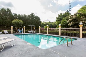 Piscina com espreguiçadeiras e cerca.