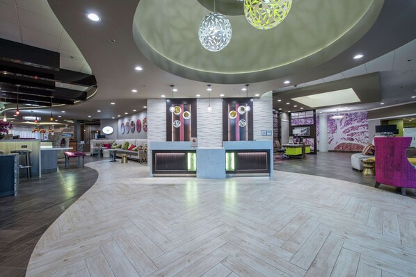 Um lobby moderno com uma receção curva, áreas de estar e um chão com padrão herringbone.