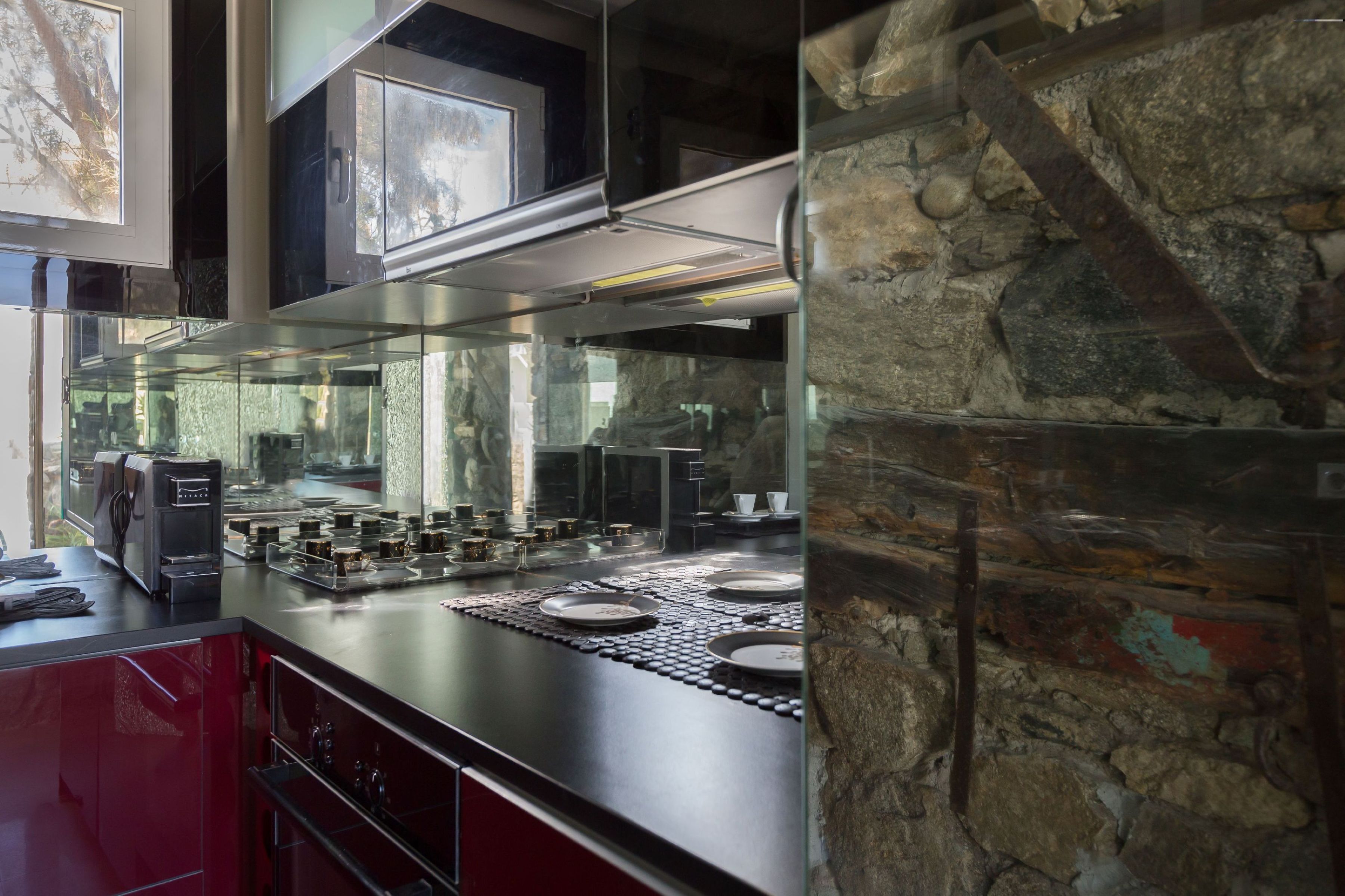 Cozinha moderna com parede de pedra e estrutura de vidro.