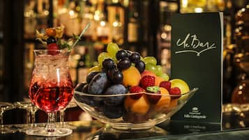 Um bar com uma fruteira e um copo de bebida vermelha.