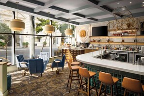 Uma área de bar moderna com balcão, banquetas e diversas garrafas.