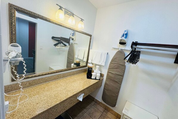 Casa de banho com um espelho grande, toucador, porta-toalhas e secador de cabelo.