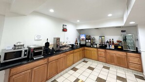 Uma cozinha com armários de madeira, micro-ondas, máquina de café e geladeira.
