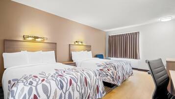 Quarto de hotel com duas camas, luminárias de cabeceira, escrivaninha e uma cadeira.
