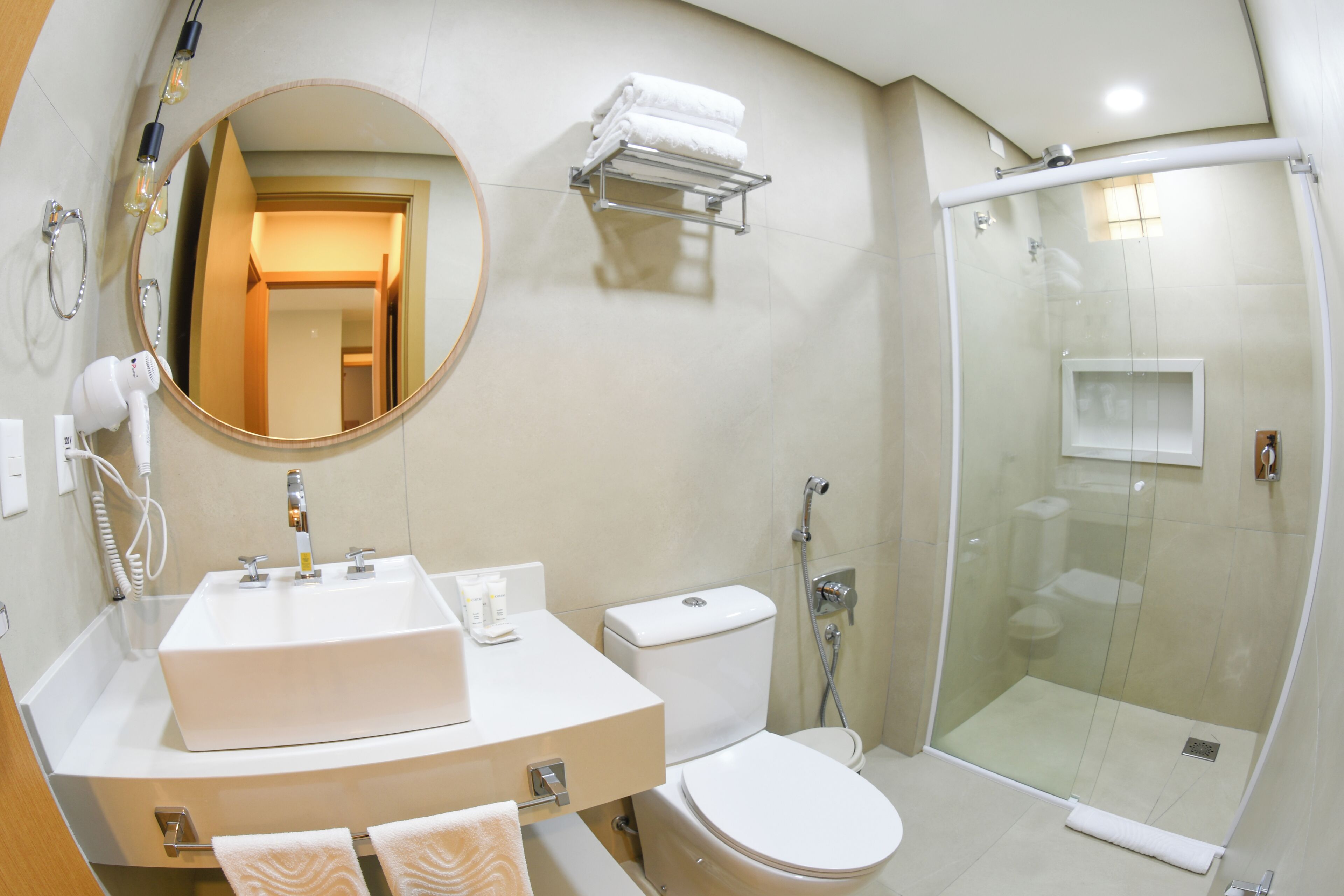 Casa de banho moderna com lavatório, sanita e cabine de duche com vidro.