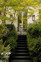 Escadaria cercada por vegetação exuberante, levando a um edifício com fachada branca.