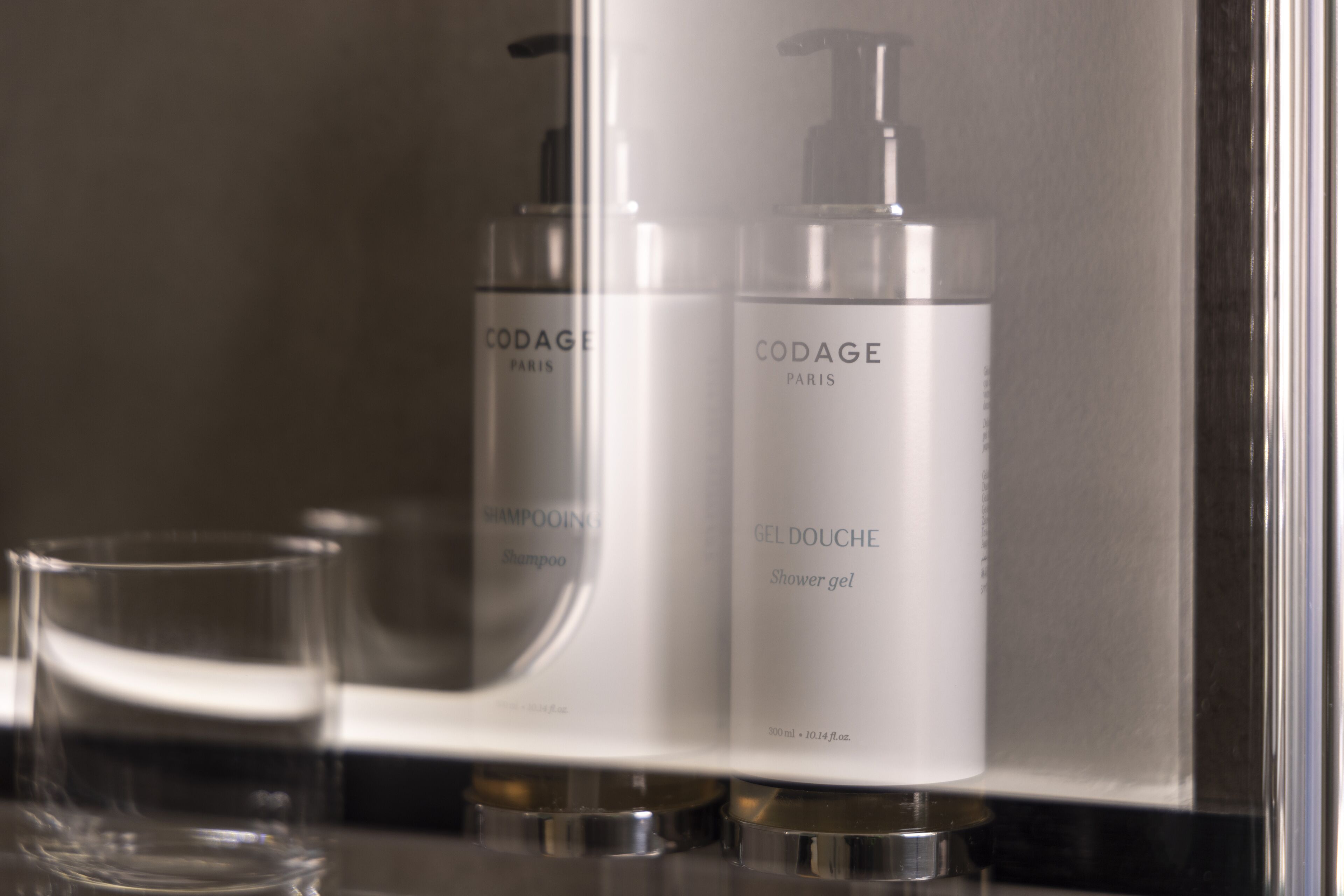 Duas embalagens de shampoo e gel de banho Codage Paris numa prateleira de casa de banho.