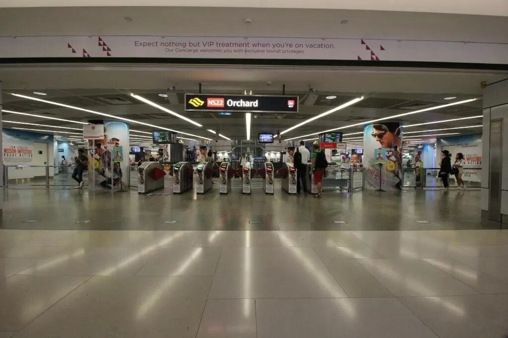 Um terminal de aeroporto espaçoso com vários balcões de check-in e uma placa com o texto 'NS22 Orchard'.