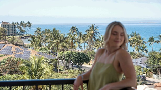 Uma varanda com vista para o mar e palmeiras.