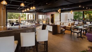 Um restaurante moderno com área de bar, disposição de assentos e grandes janelas com vista para o exterior.
