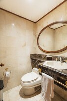 Casa de banho com sanita, lavatório, espelho e porta-toalhas.