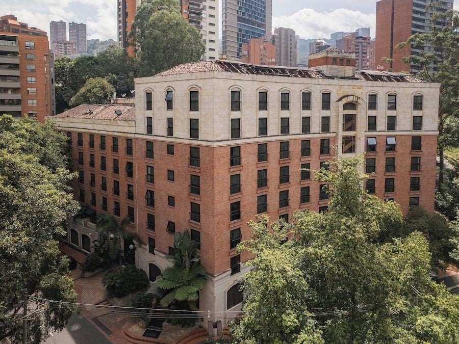 Um edifício de vários andares com fachada de tijolos, grandes janelas e um pátio central.
