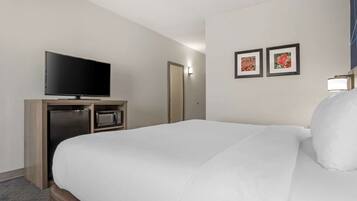 Quarto de hotel com cama, televisão, micro-ondas e frigorífico.