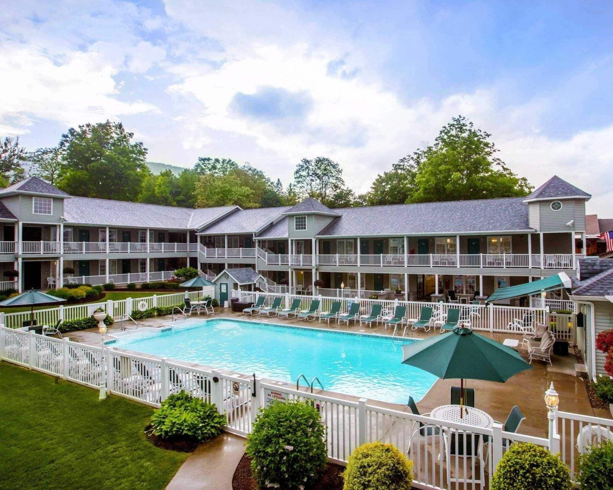 Um hotel com uma piscina grande ao ar livre, várias varandas e um jardim bem cuidado.